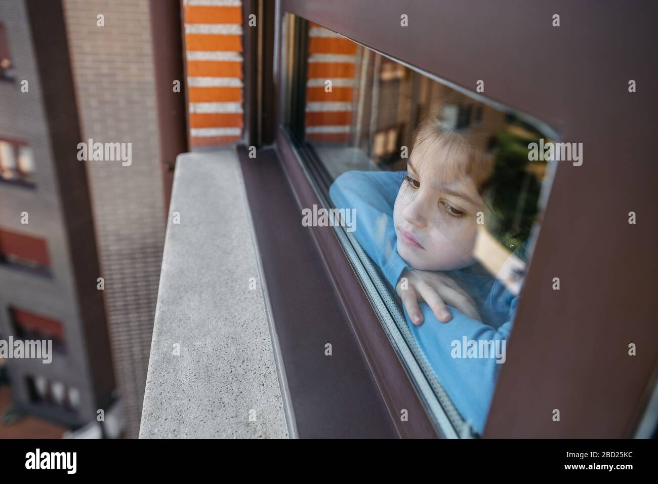 Sad girl looking out the window Stock Photo - Alamy