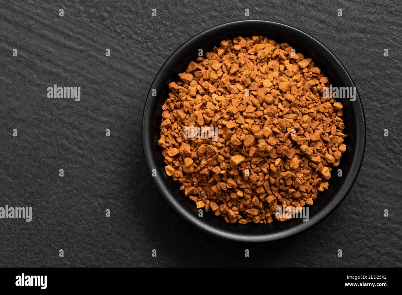 Dry instant coffee in a black ceramic dish isolated on black. Top view ...