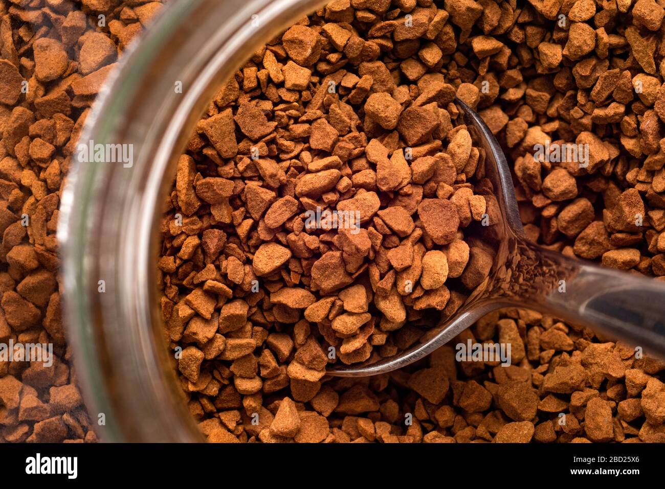 Detail of dry instant coffee in an open glass jar with metal spoon. Top ...