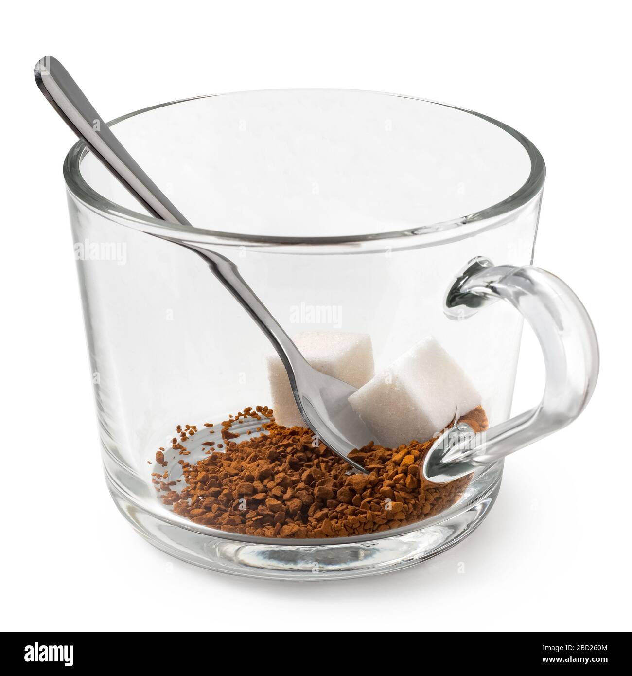 Dry instant coffee and cubes of sugar in a glass mug with metal spoon ...