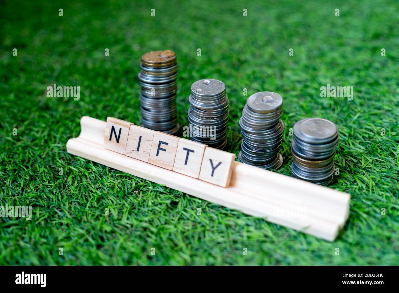 Wooden blocks with NIFTY written on them with a growing stack of coins ...