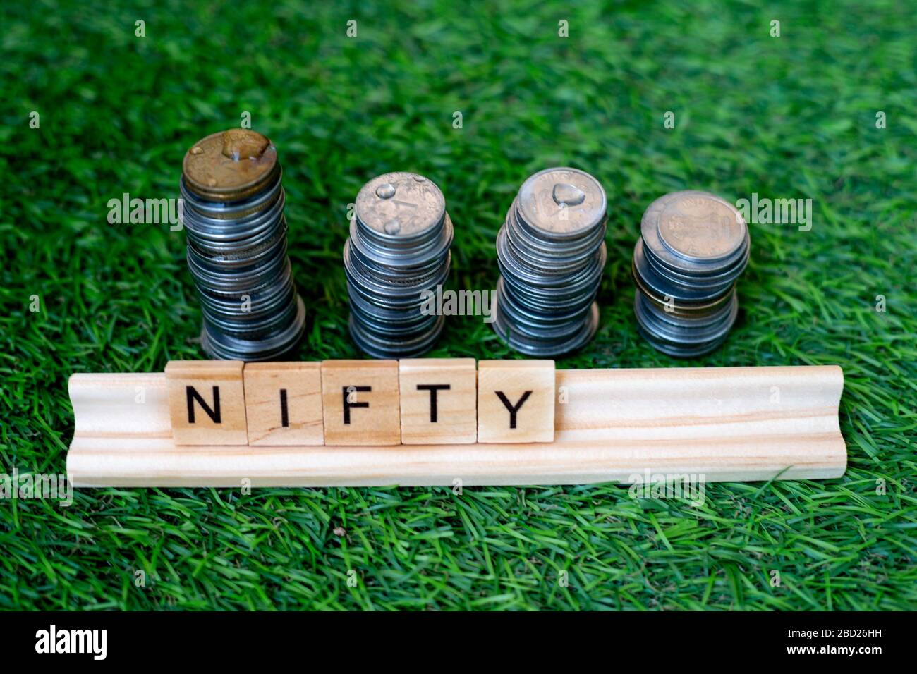 Wooden blocks with NIFTY written on them with a growing stack of coins ...