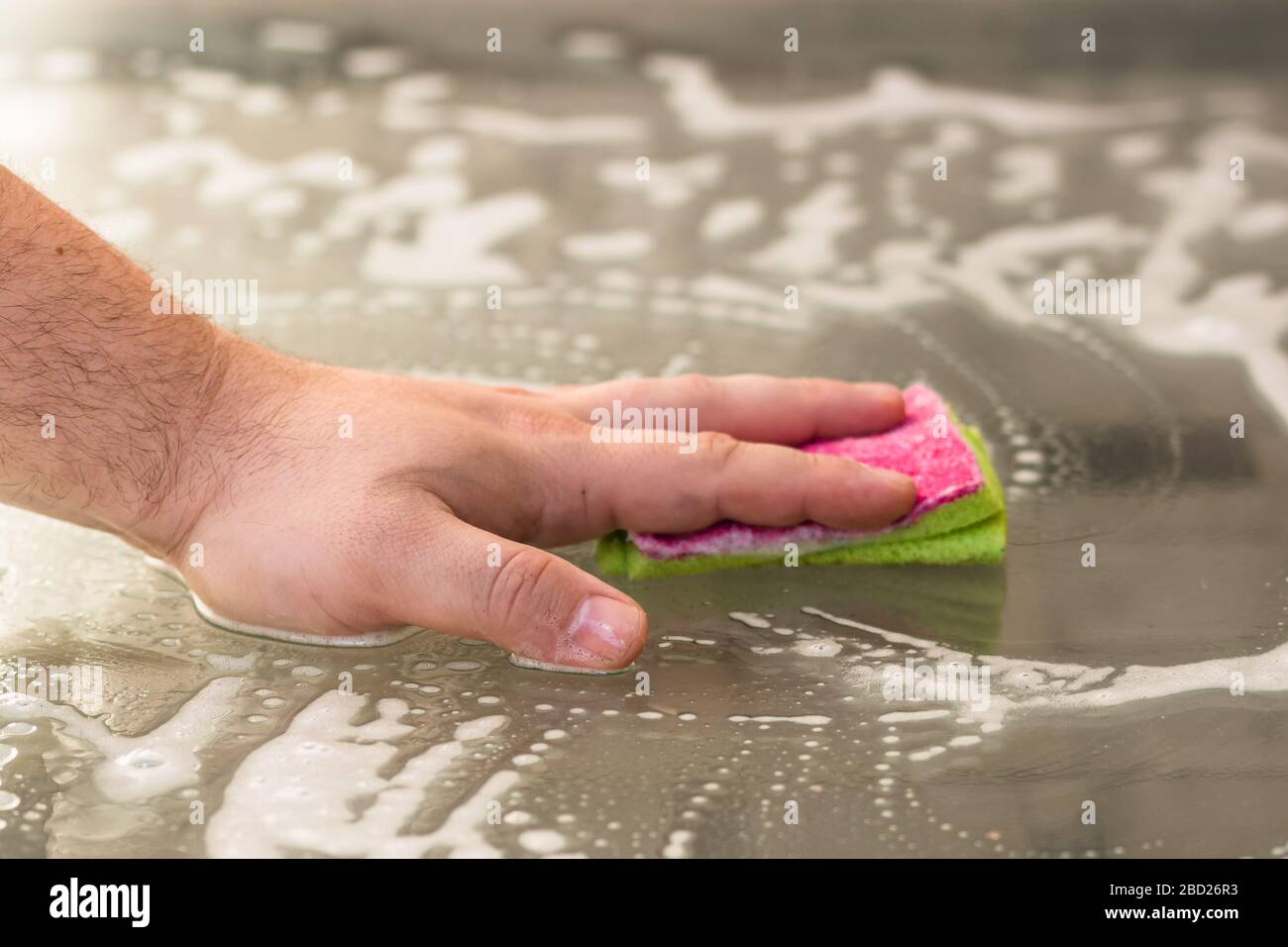 Man cleaning glass table using sponge and cleaning sprayer, cleaning ...