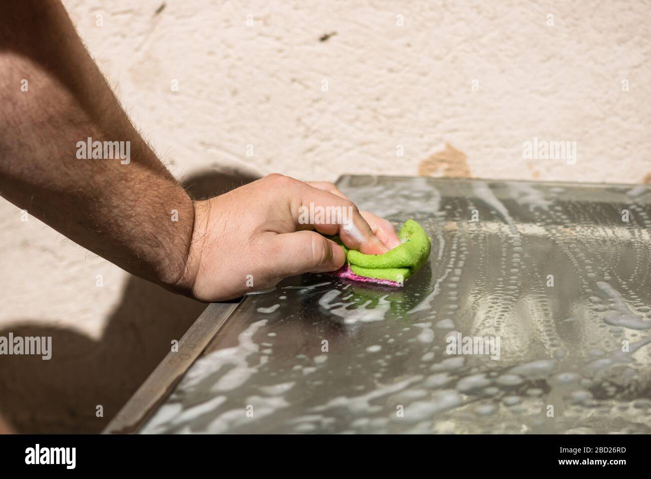 Man cleaning glass table using sponge and cleaning sprayer, cleaning ...