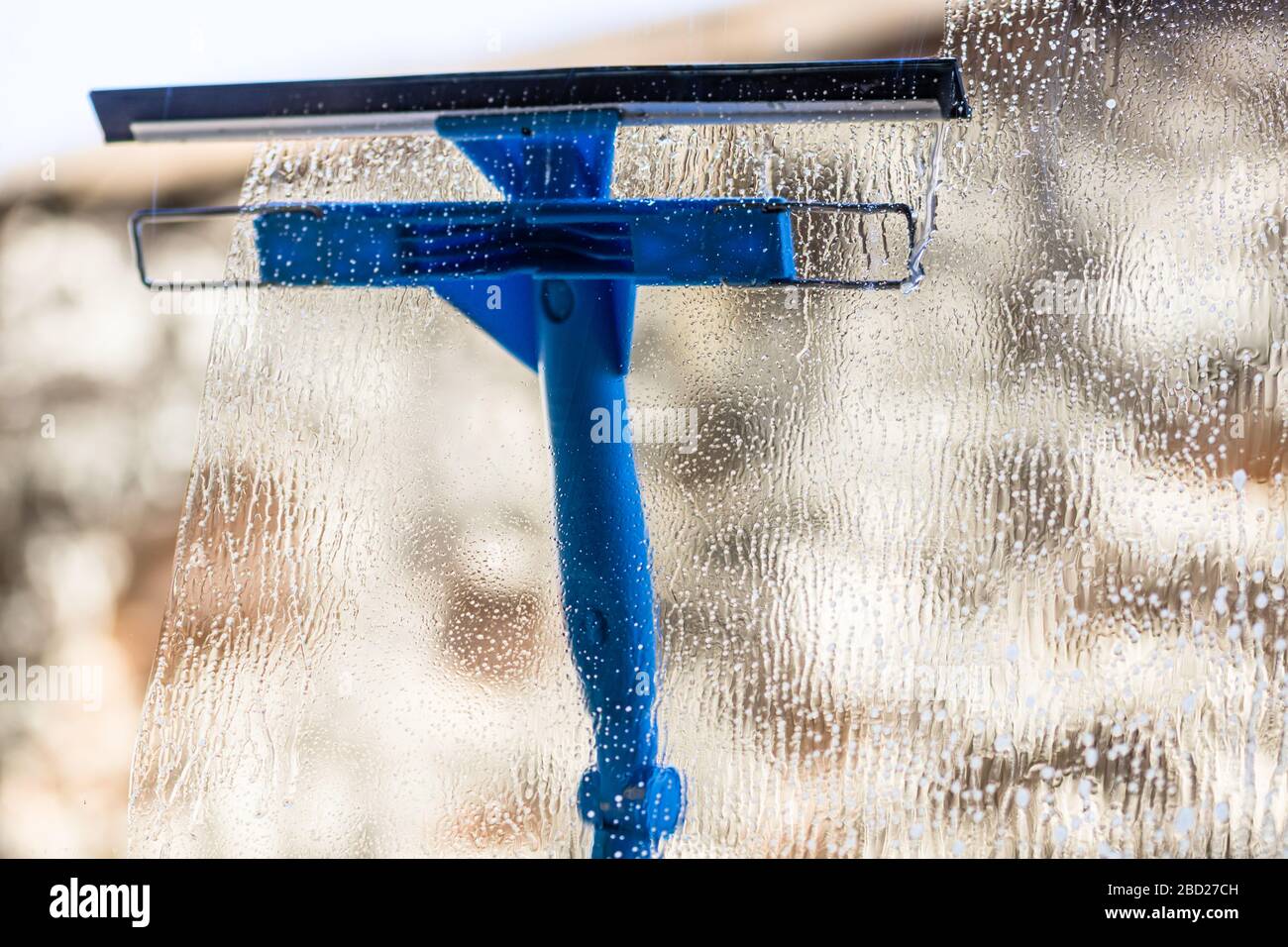 Man cleaning window using window cleaning squeegee and cleaning sprayer ...