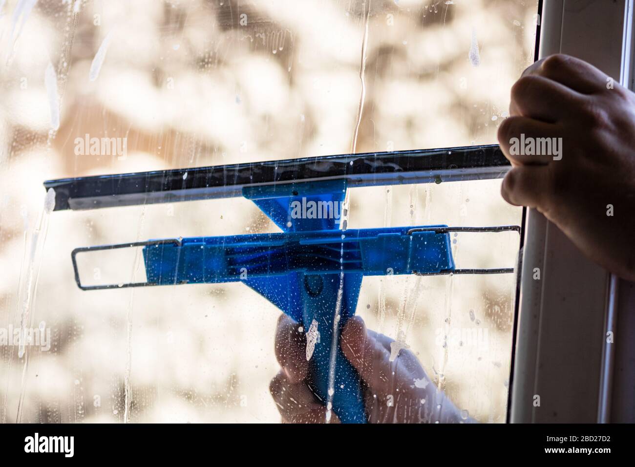 Man cleaning window using window cleaning squeegee and cleaning sprayer ...
