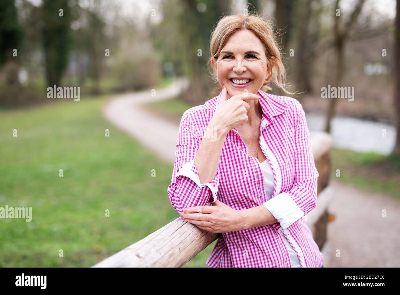 An attractive woman with a sympathetic laugh in nature while walking ...