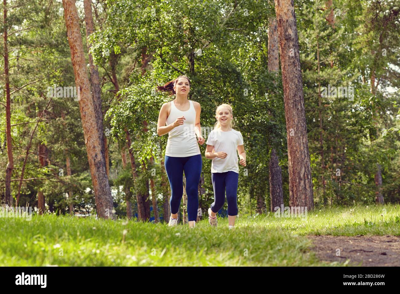 running sporty mother and daughter. woman and child jogging in a park ...