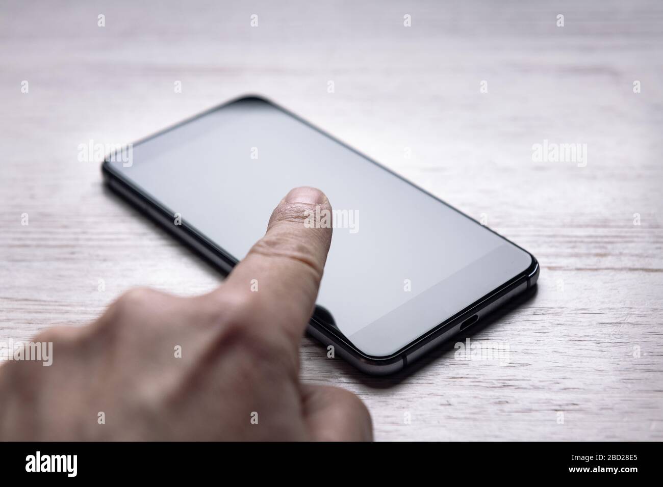 finger touching the screen of a smart phone with blank screen on white ...
