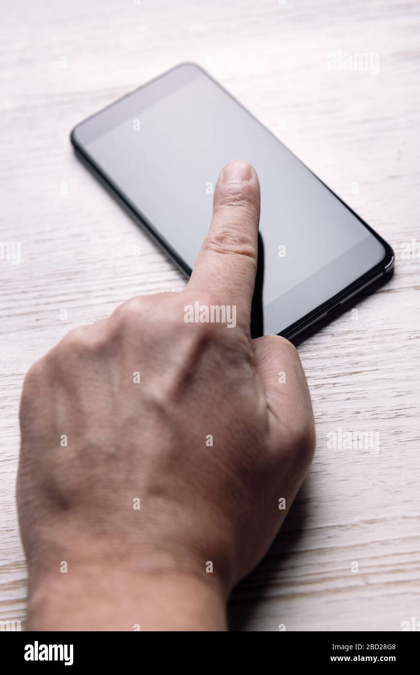 vertical photo of a hand with the finger touching the screen of a smart ...
