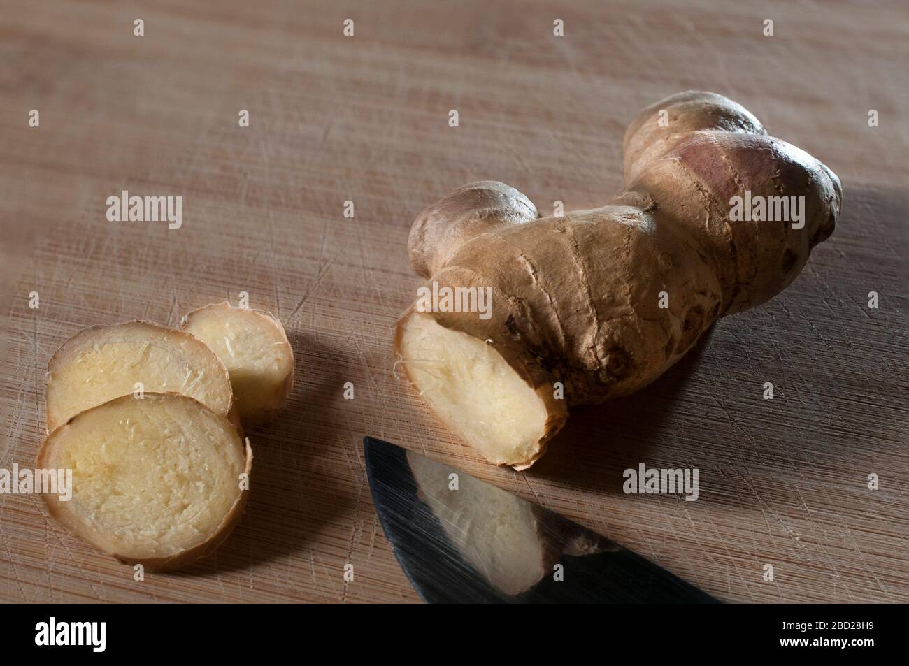 Ginger on a cutting board with ginger slices cut with a knife and rim ...