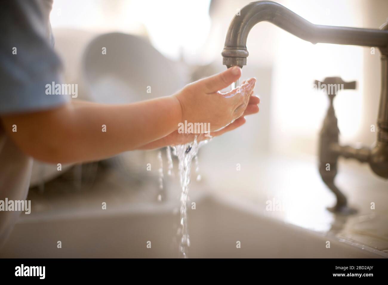 Toddler holding hands under tap Stock Photo - Alamy