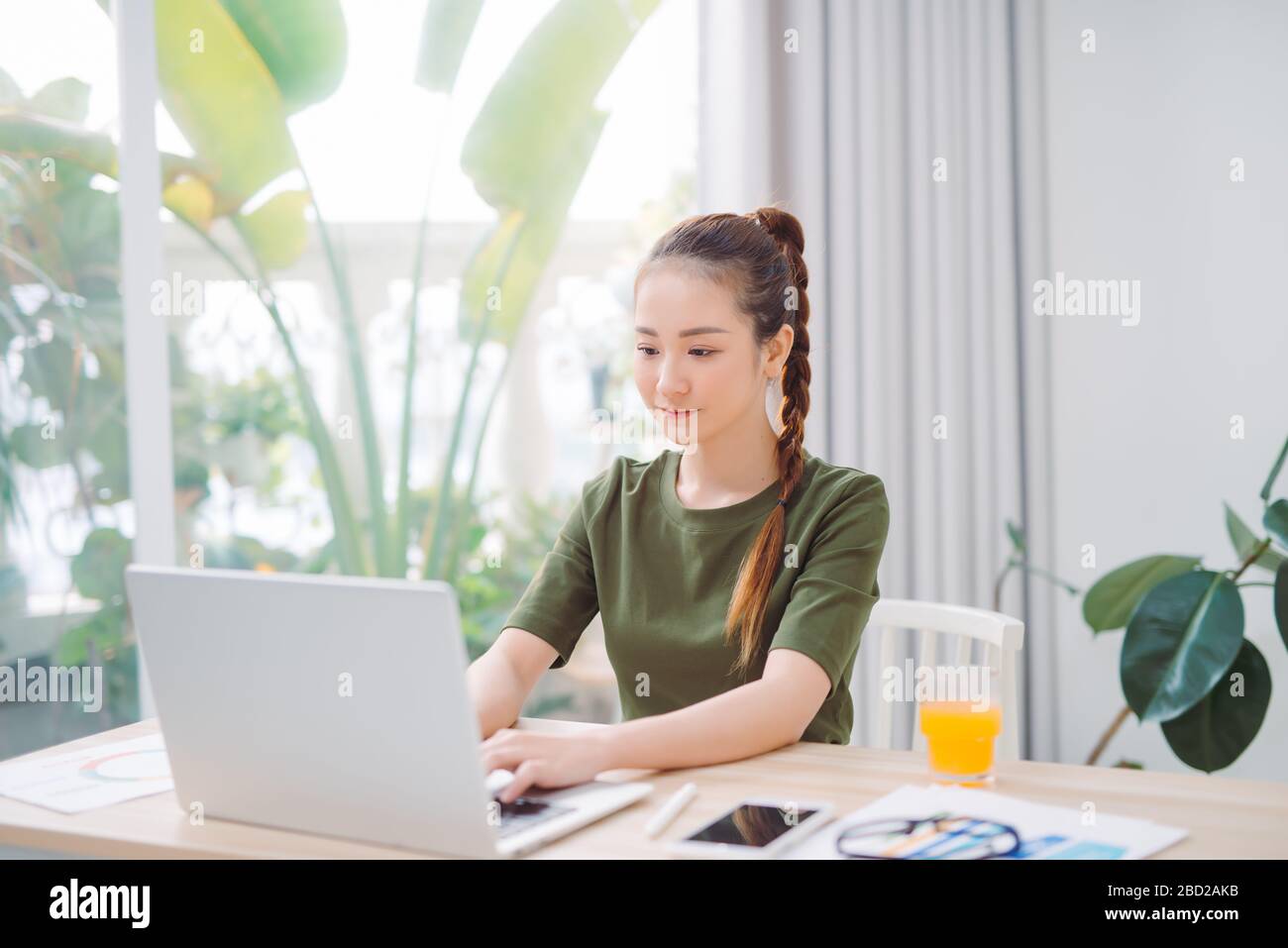 Pretty asian woman typing email on laptop computer while sitting at ...