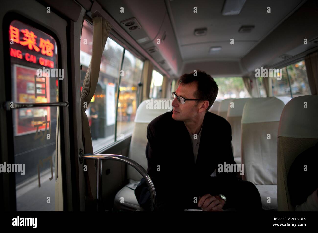 Mid-adult man sitting alone inside a small bus Stock Photo - Alamy