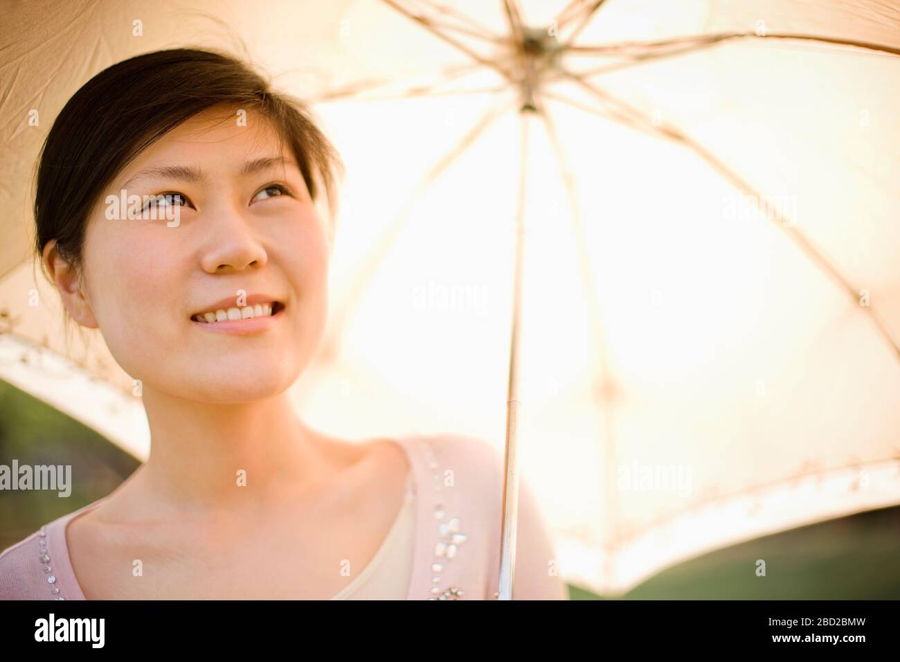 Smiling young woman standing underneath an umbrella Stock Photo - Alamy