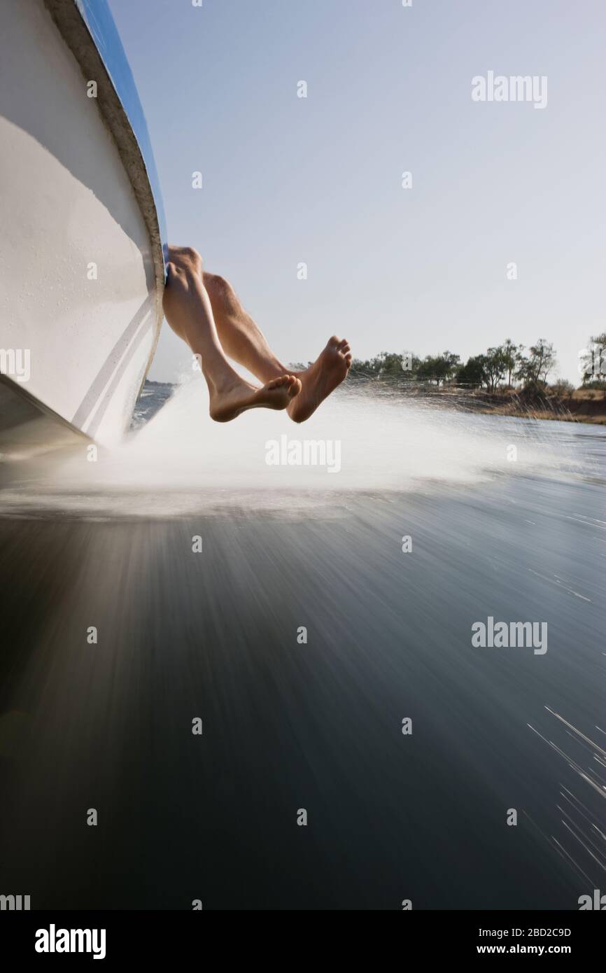 Legs dangling off the side of a boat Stock Photo - Alamy