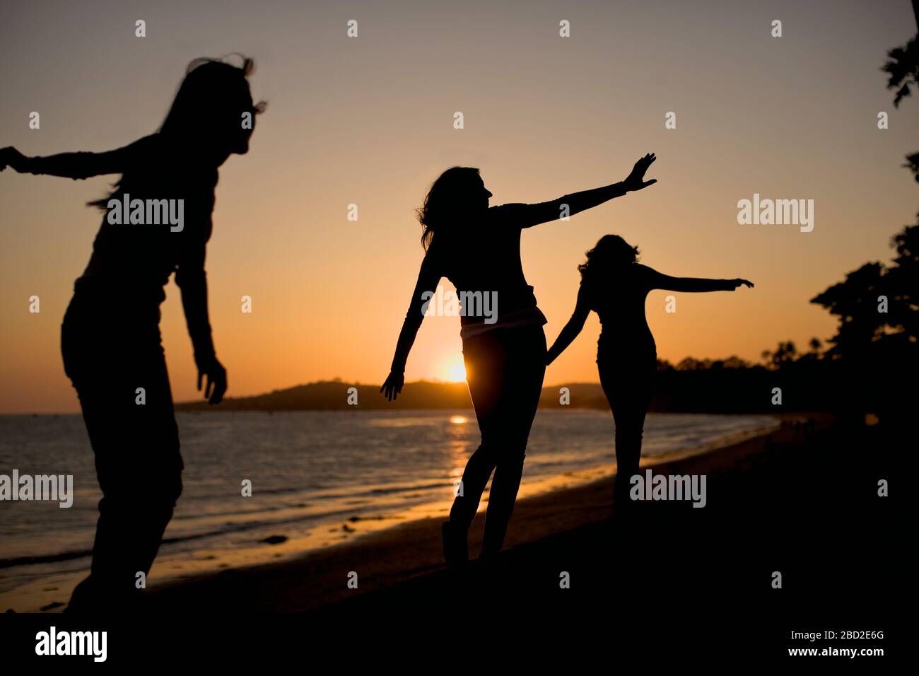 Three women balancing on a wall at the beach Stock Photo - Alamy