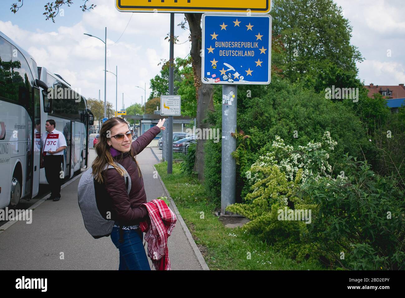 A young woman is crossing a German border, pointing at the road sign ...