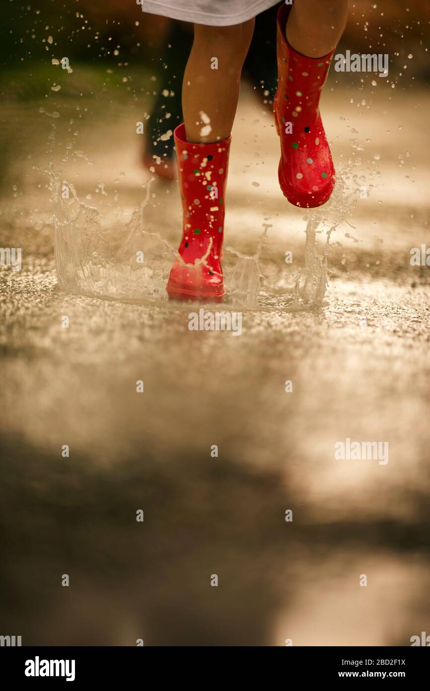 Red gumboots splashing through a rain puddle Stock Photo - Alamy