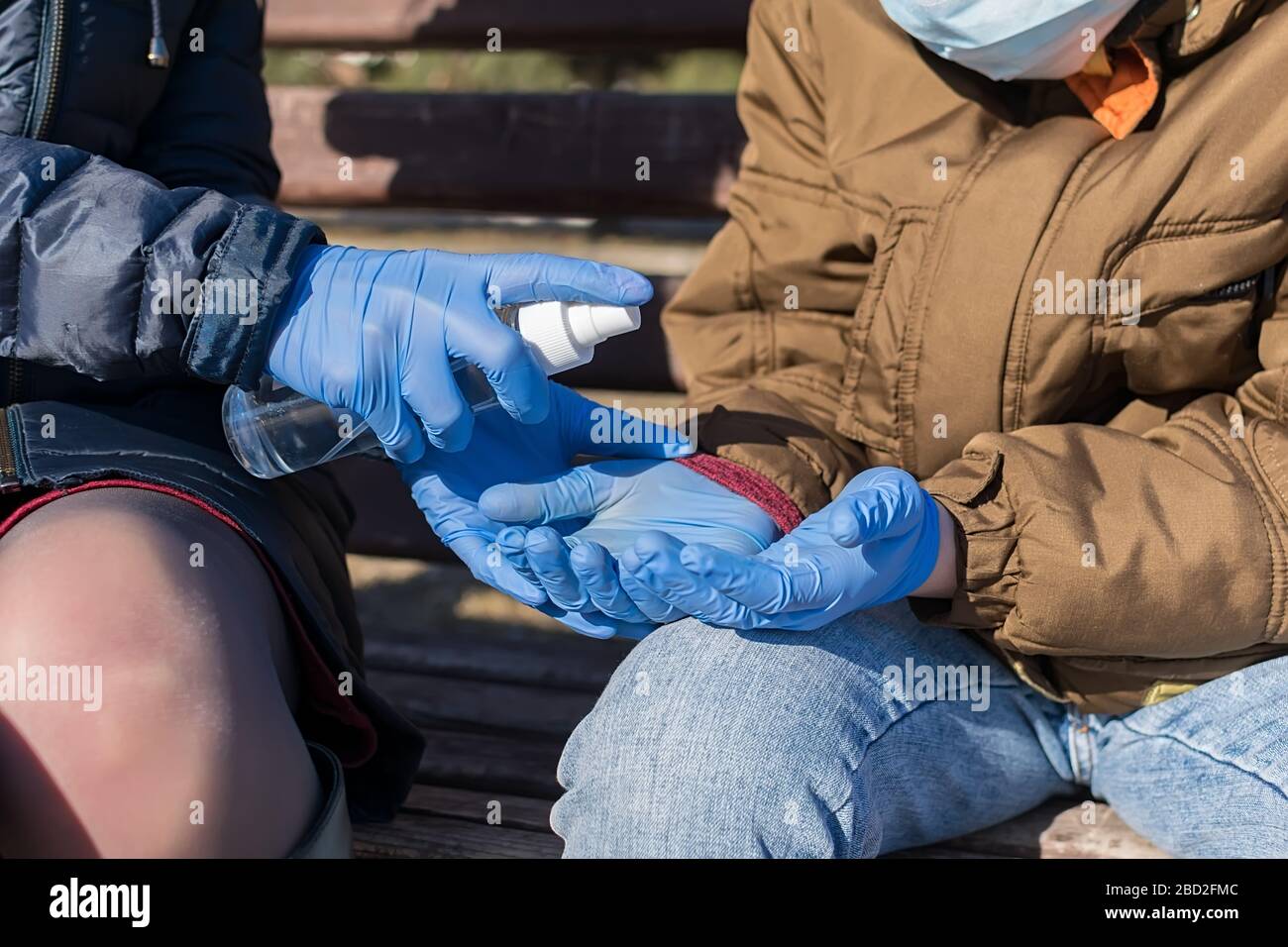 a mother with a child sprays her hands with an anti bacterial anti ...