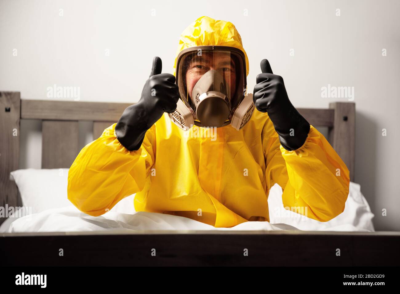 male self isolating in bed wearing a hazmat suit and mask with his ...