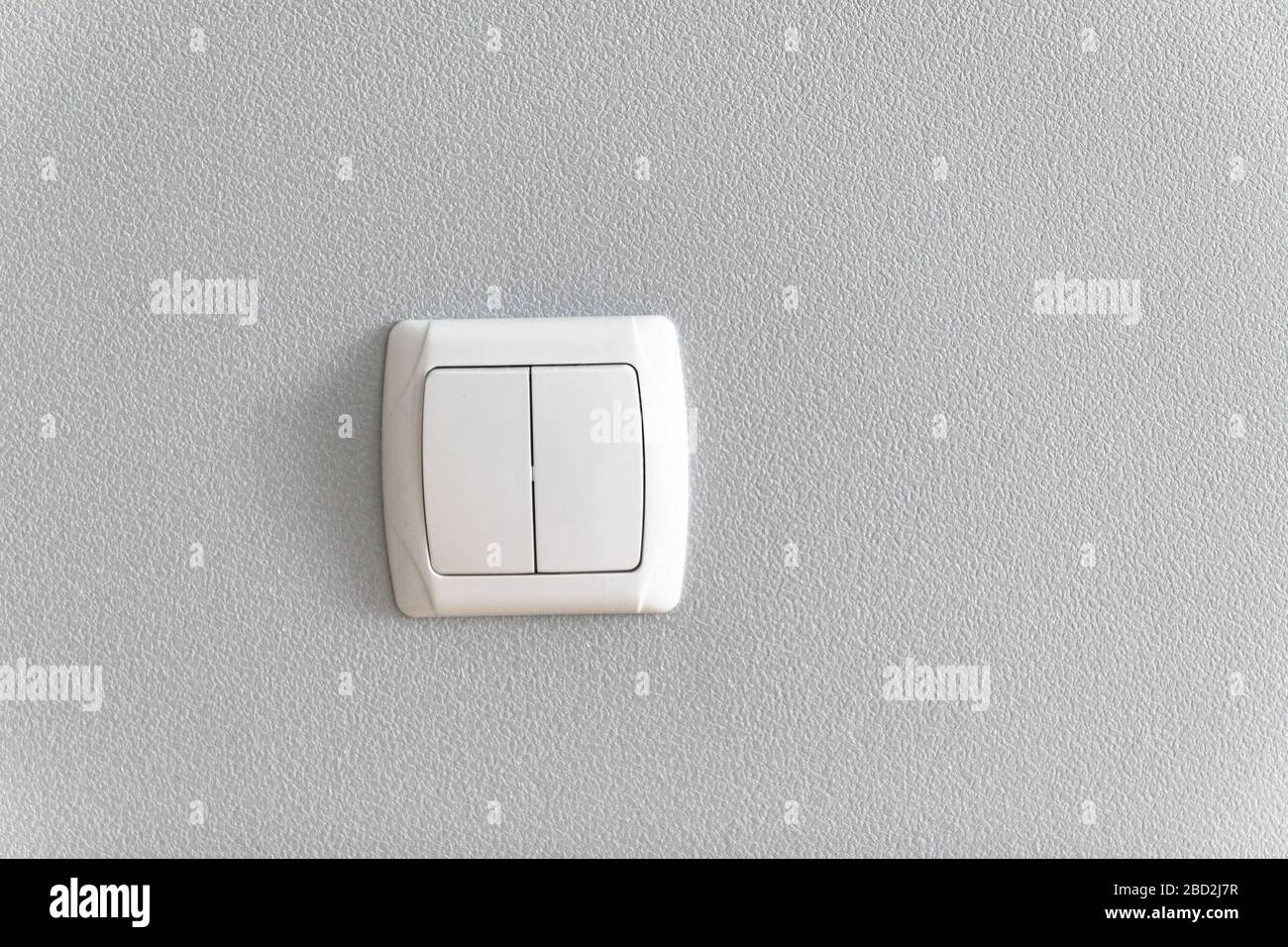 light switch, a white plastic mechanical switch mounted on a light gray ...
