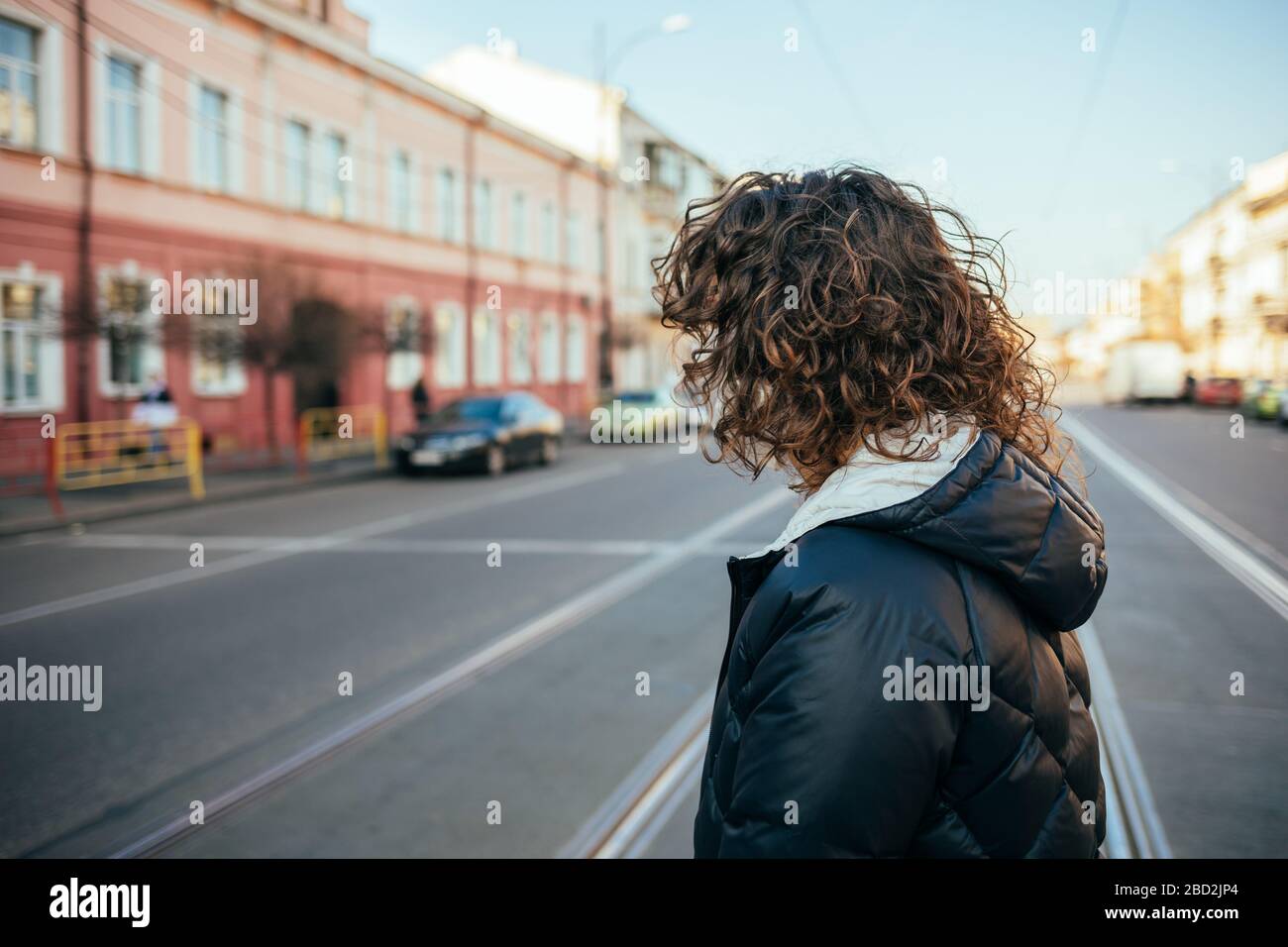Side view unrecognizable young woman with curly hair crosses road in ...