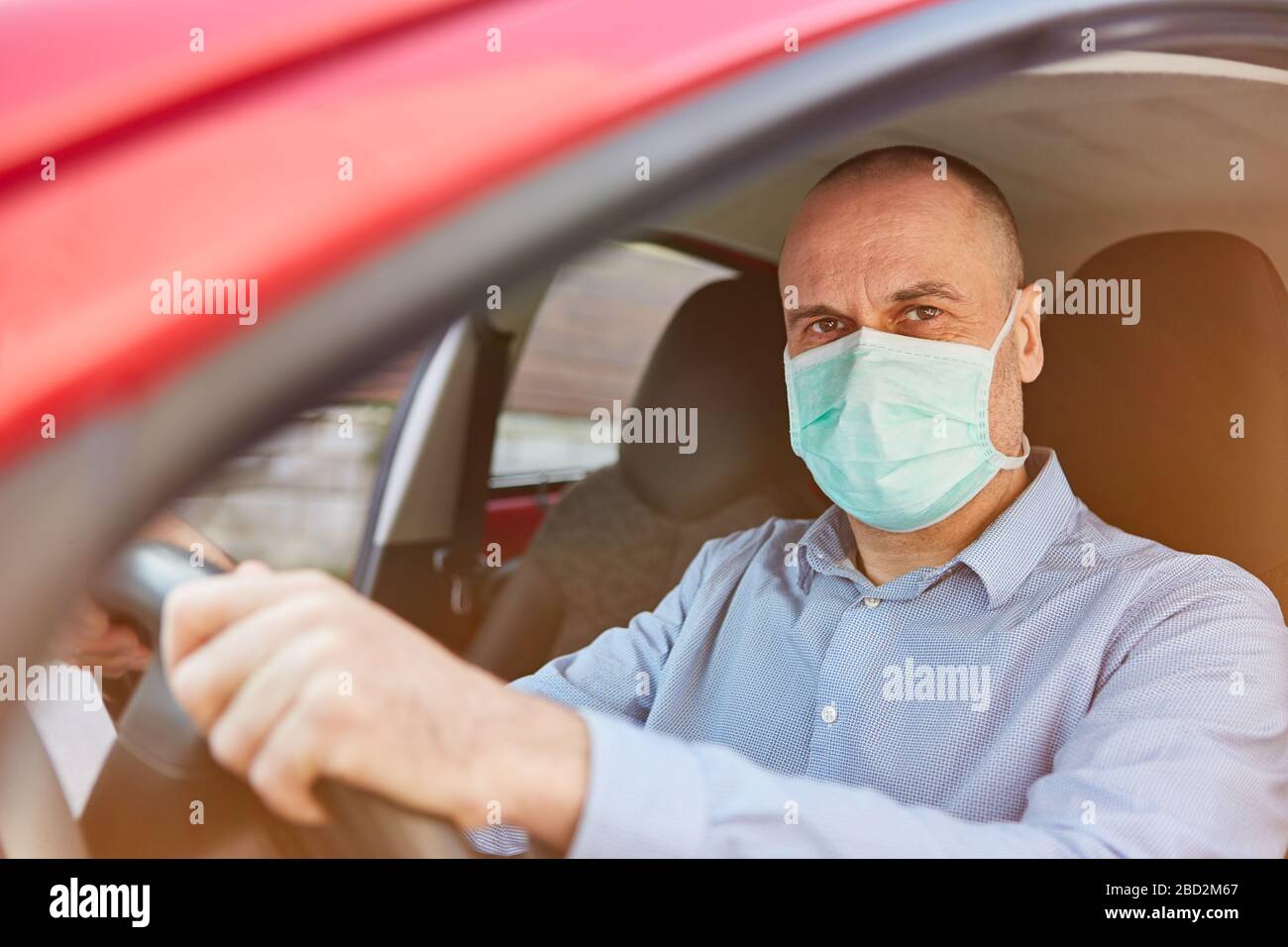 Senior with face mask while driving in Covid-19 coronavirus pandemic ...