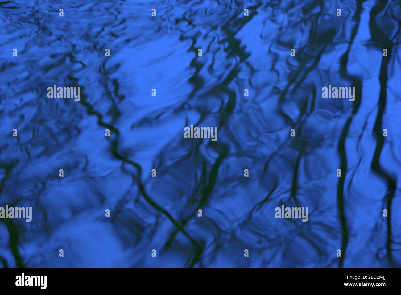 Abstract Blurred Trees Mirrored Reflection On Rippled Water Surface In Classic Blue Color Toning