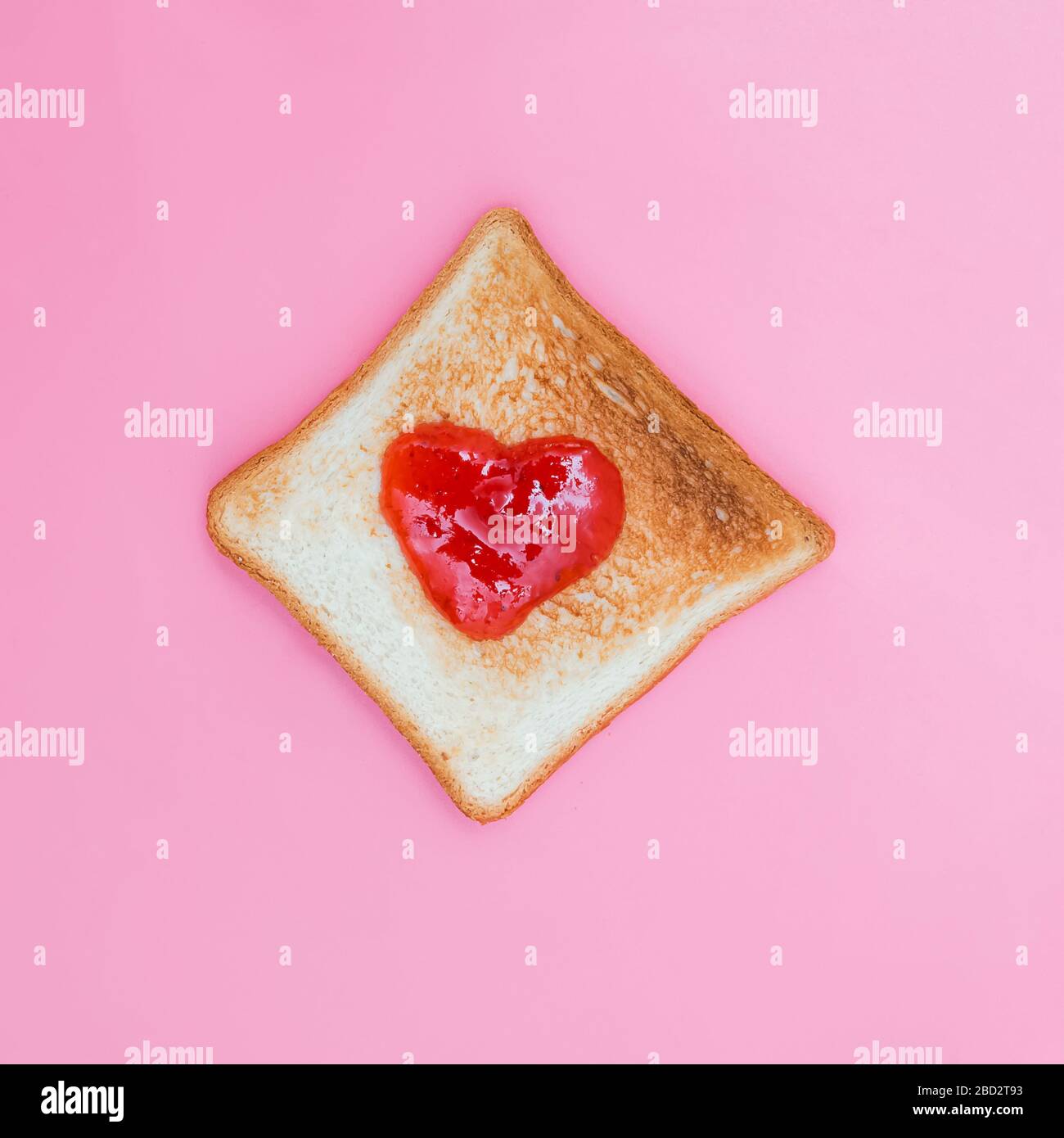 Toasted bread with strawberry jam in heart shape on pink background ...
