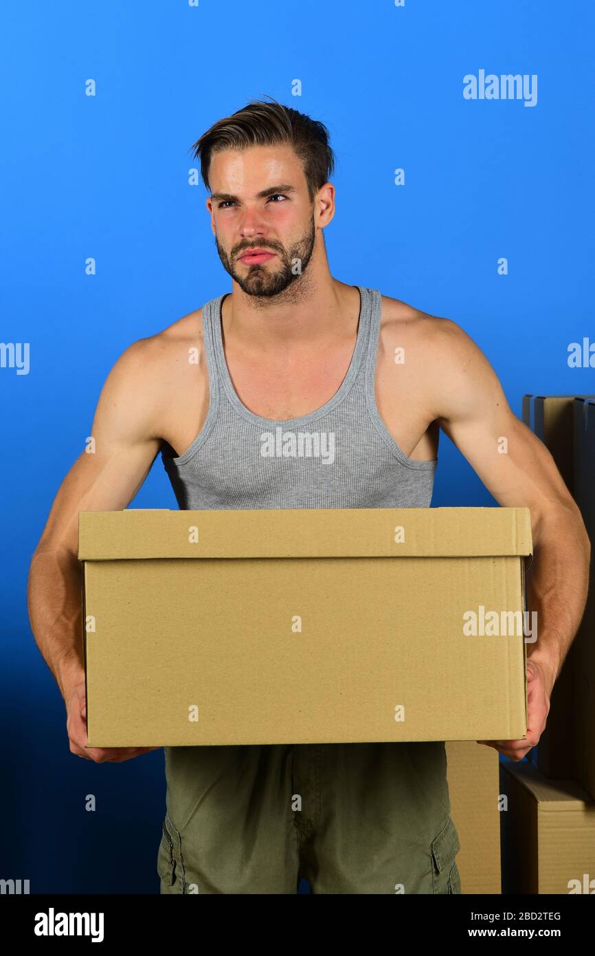 Man standing among cardboard boxes and holding one. Macho with beard ...