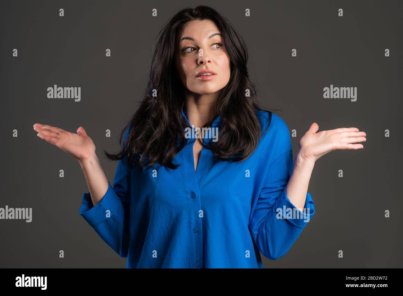 Mature unsure woman shrugs her arms, makes gesture of I don't know ...