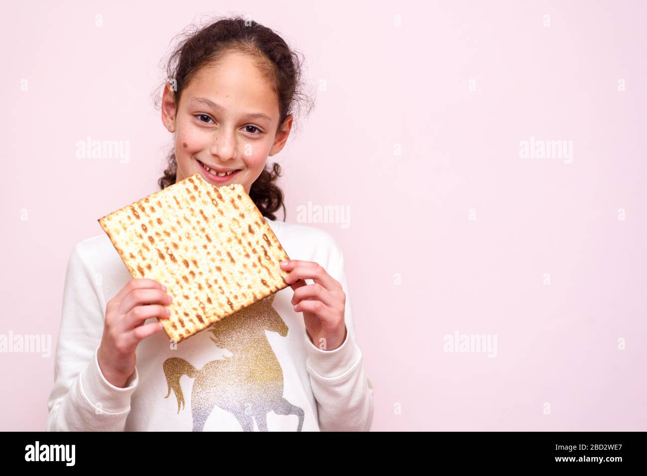 Portrait of the cute teenager girl holding matzah. Jewish child eating ...