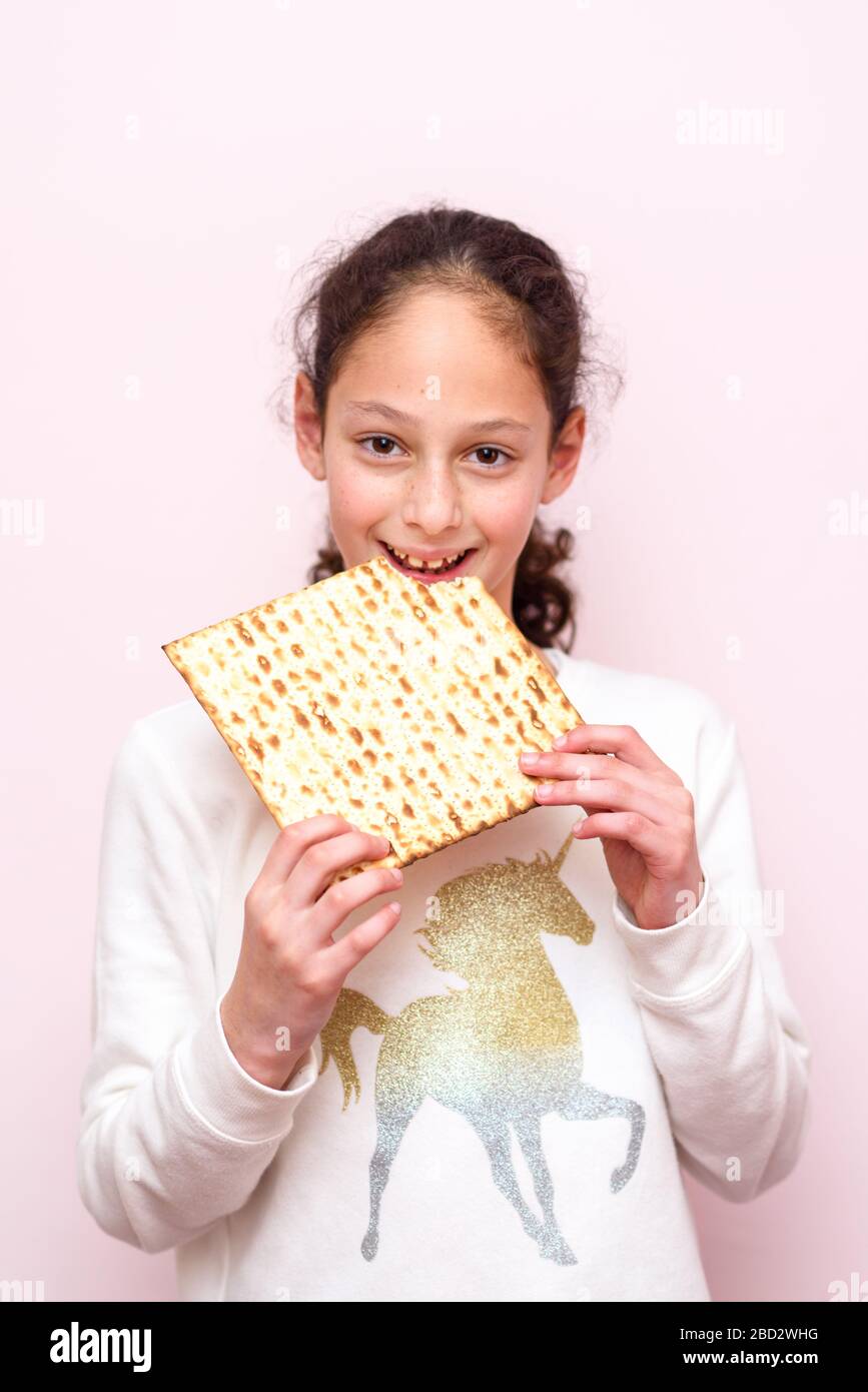 Portrait of the cute teenager girl holding matzah. Jewish child eating ...