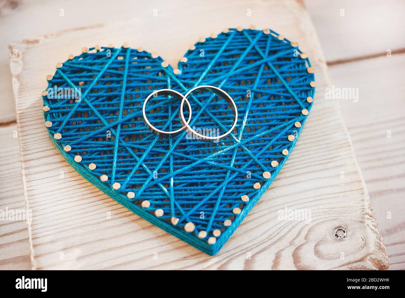 Close up view on string art heart with two wedding rings on it. Wedding ...