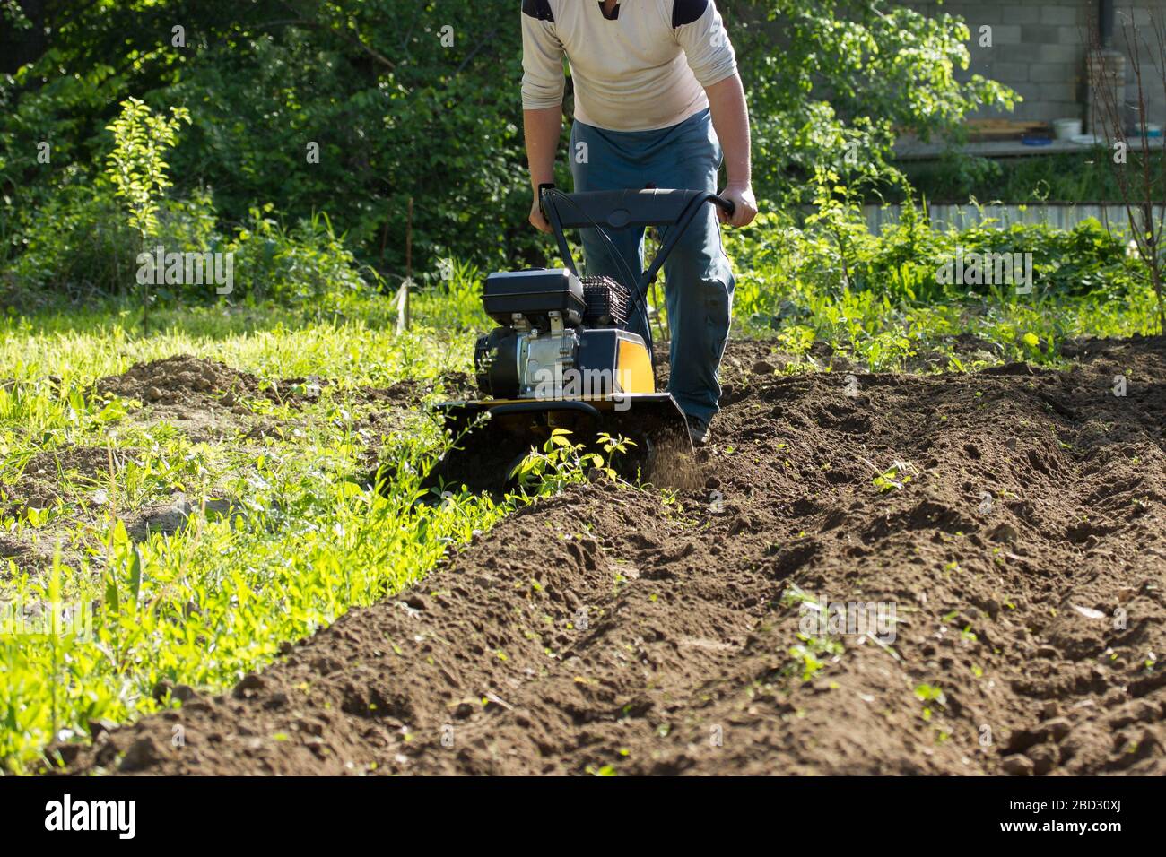 Perspective view of man plowing garden soil by motor cultivator Stock ...