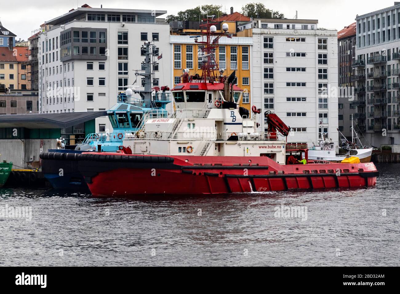 Tug boat BB Worker moored in port of Bergen, Norway. A rainy and foggy day. Tug boat Vivax in ...