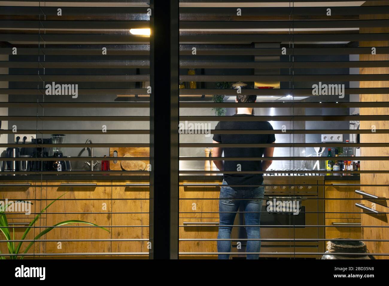 A man standing in a cozy kitchen cooking dinner in the evening Viewed ...