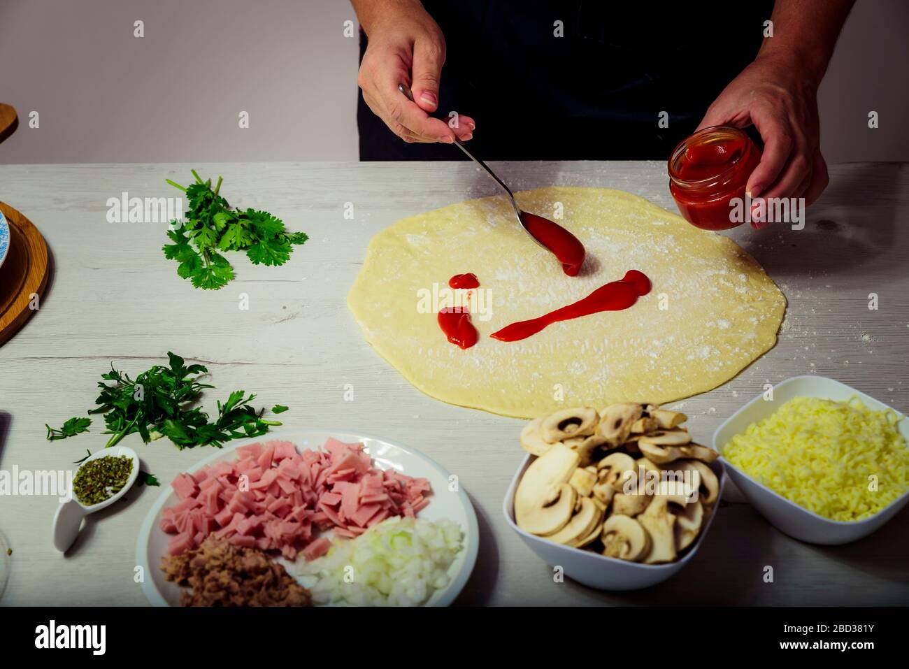 Woman adding ingredients to homemade pizza dough. cooking concept Stock ...