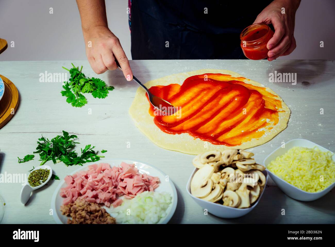 Woman adding ingredients to homemade pizza dough. cooking concept Stock ...