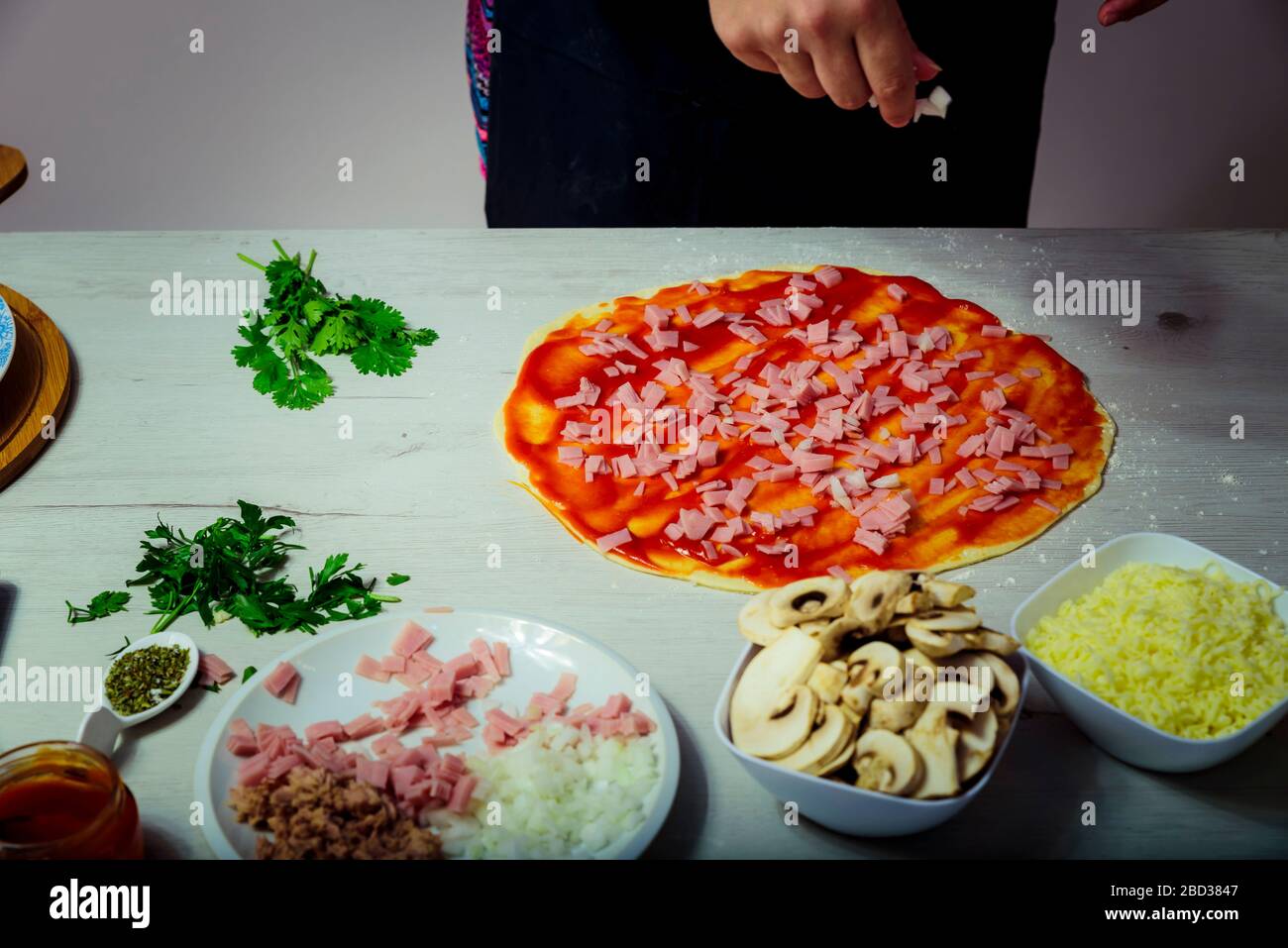 Woman adding ingredients to homemade pizza dough. cooking concept Stock ...