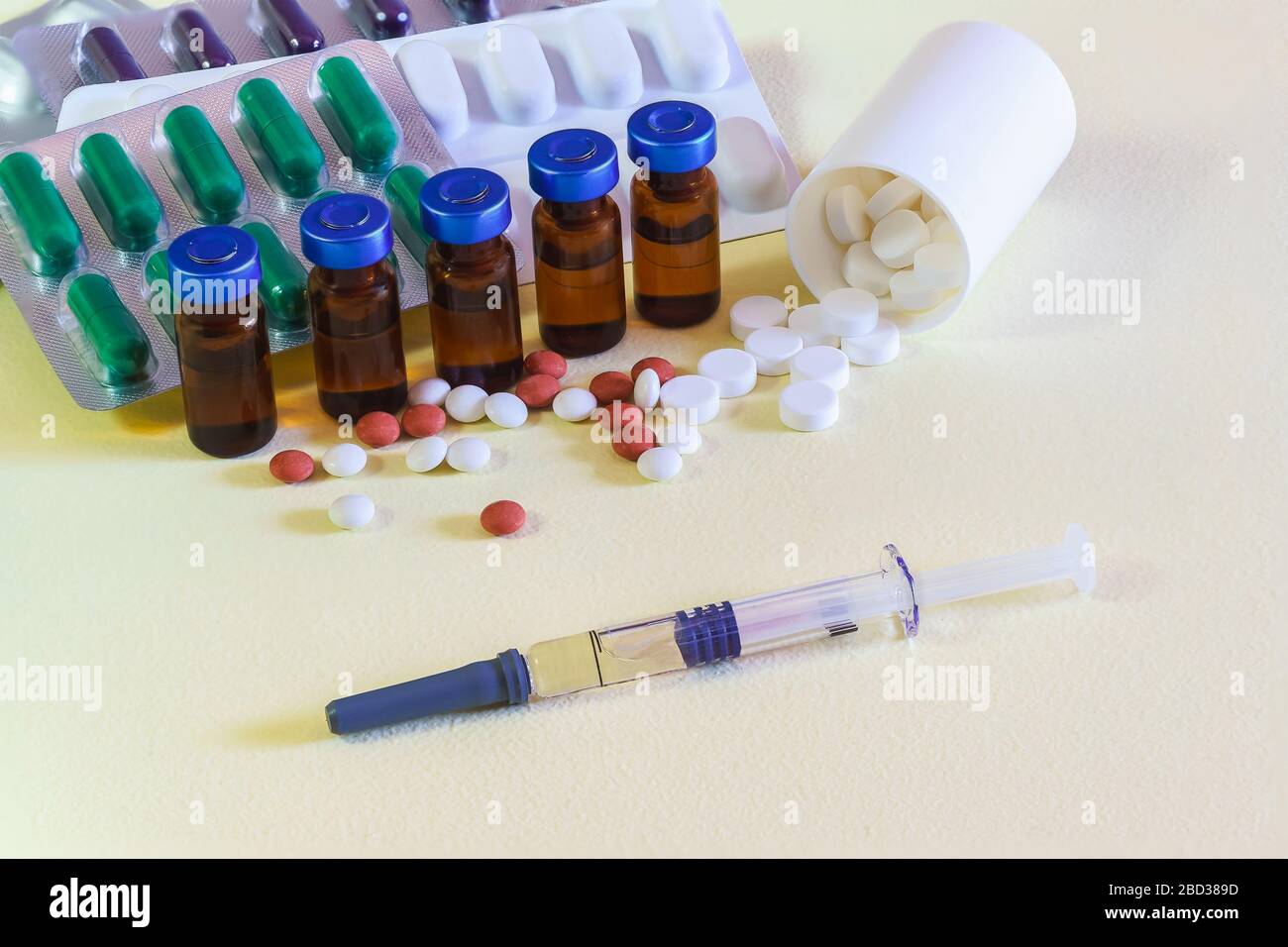 Vials of injectable drugs and scattered pills on the table. A syringe ...