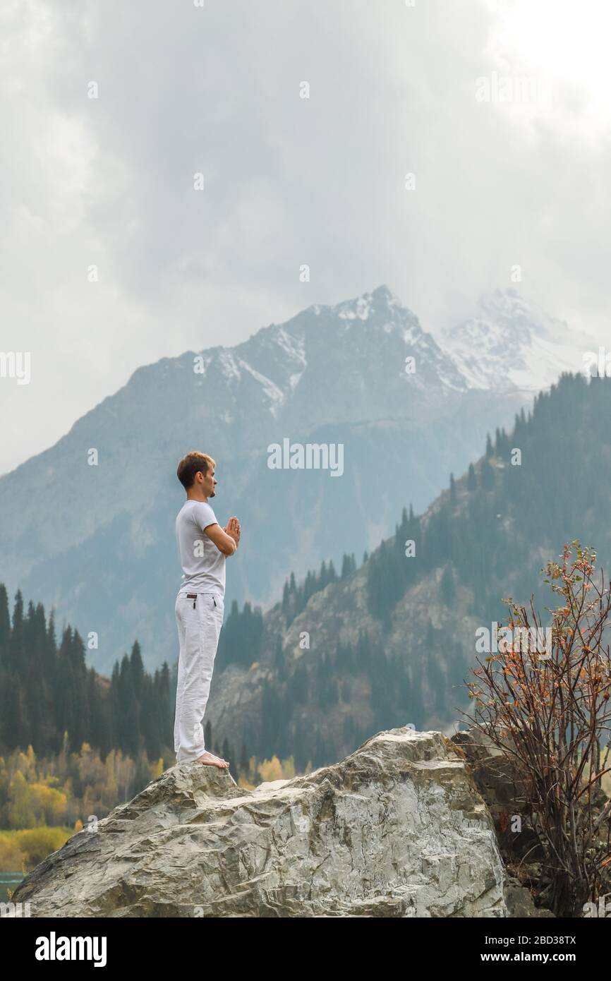 A man in a Samasthiti pose on a stone among a mountain lake Stock Photo ...