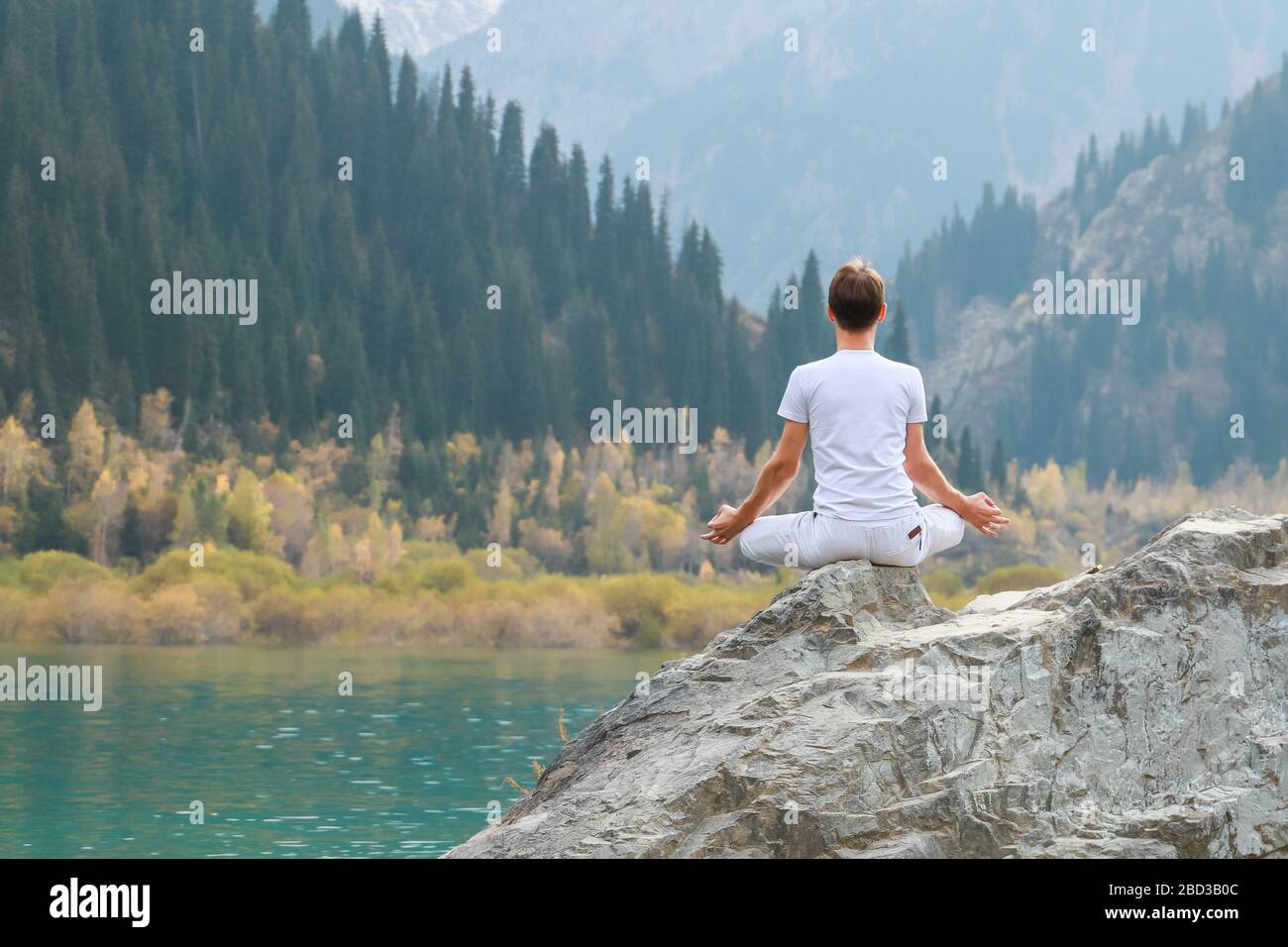 Young zen man in meditation. Outdoor yoga in mountain lake. Exercise ...