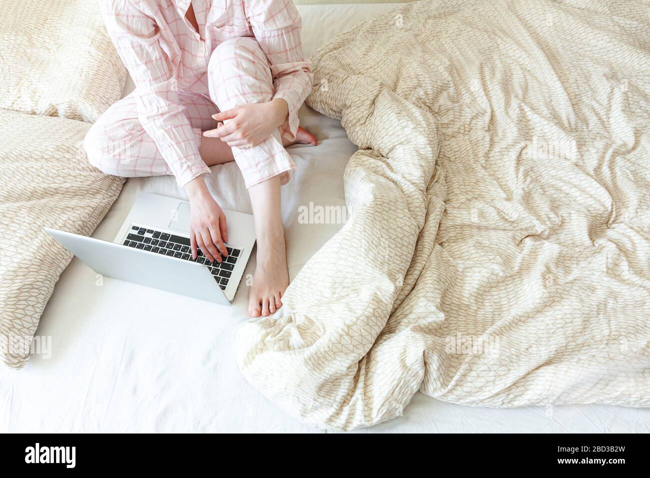 Mobile Office at home. Young woman in pajamas sitting on bed at home ...