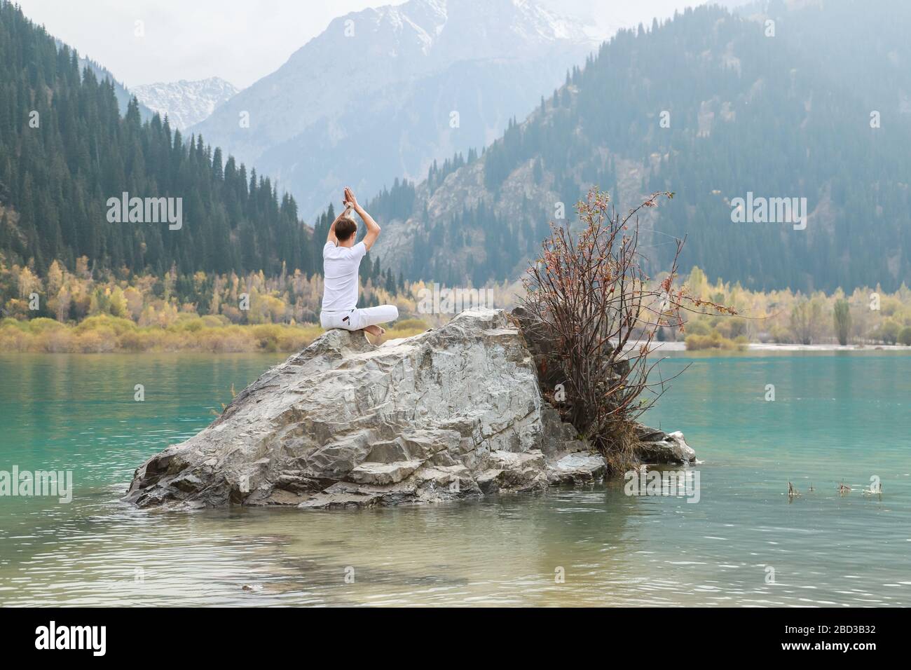 Young zen man in meditation. Outdoor yoga in mountain lake. Exercise ...