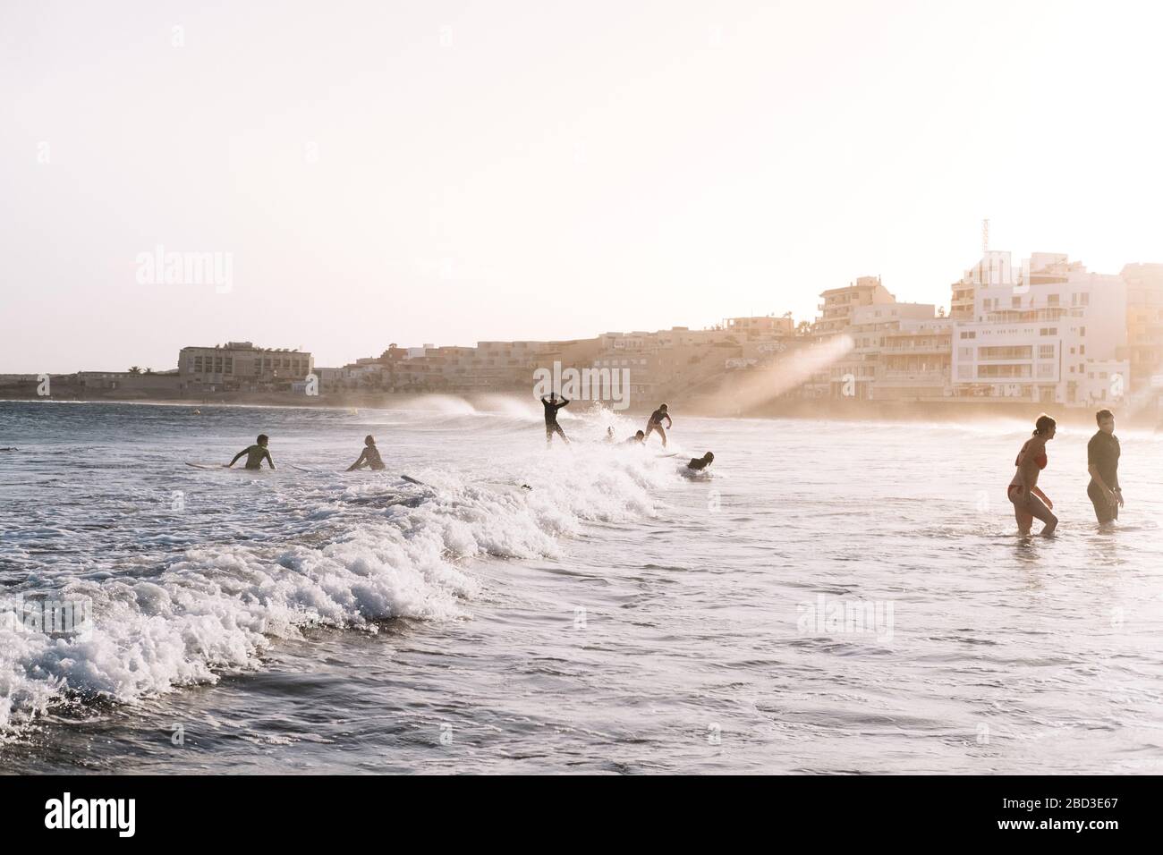 Pulled back view of surfers and people on the beach at sunset Stock ...