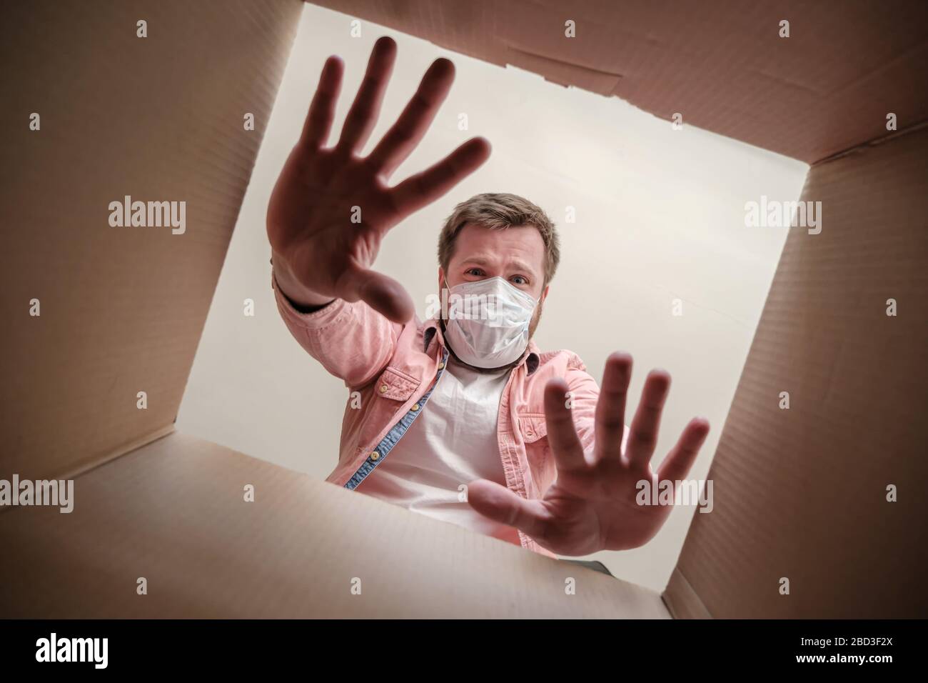 Frightened man in a medical mask unboxing inside view a delivered box ...