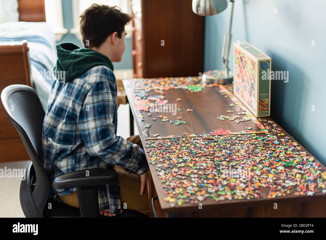 Teen Boy Working On A Jigsaw Puzzle In His Bedroom During Covid 19