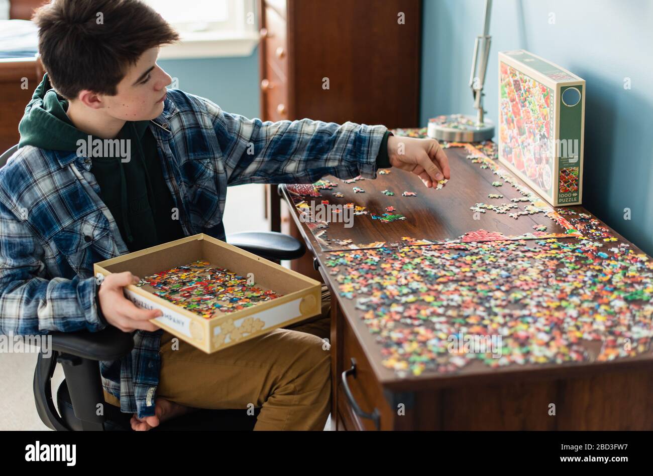 Teen boy working on a jigsaw puzzle in his bedroom during Covid 19 ...
